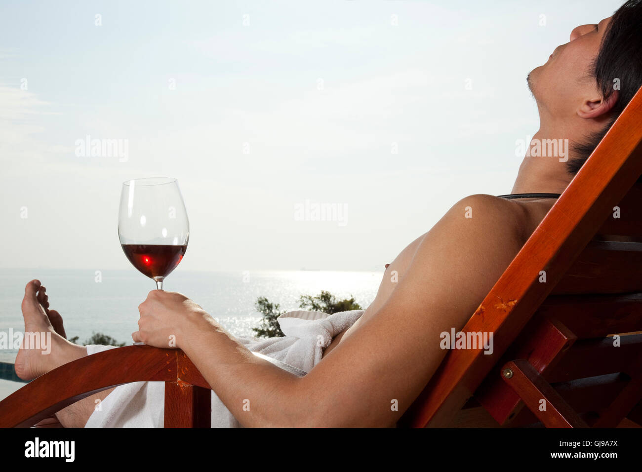 Young men lounge by the pool drinking wine Stock Photo - Alamy