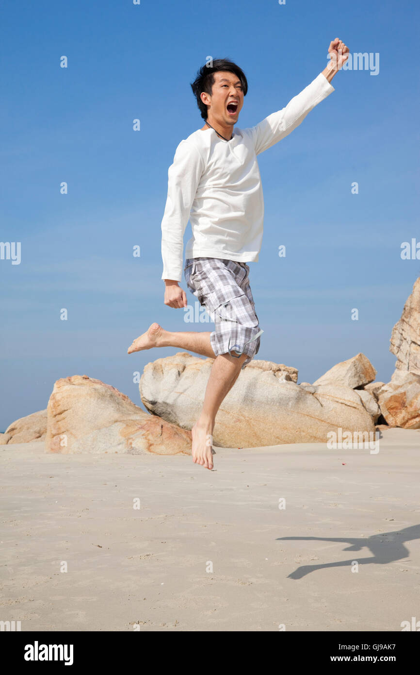 Young man jumping at the beach Stock Photo - Alamy