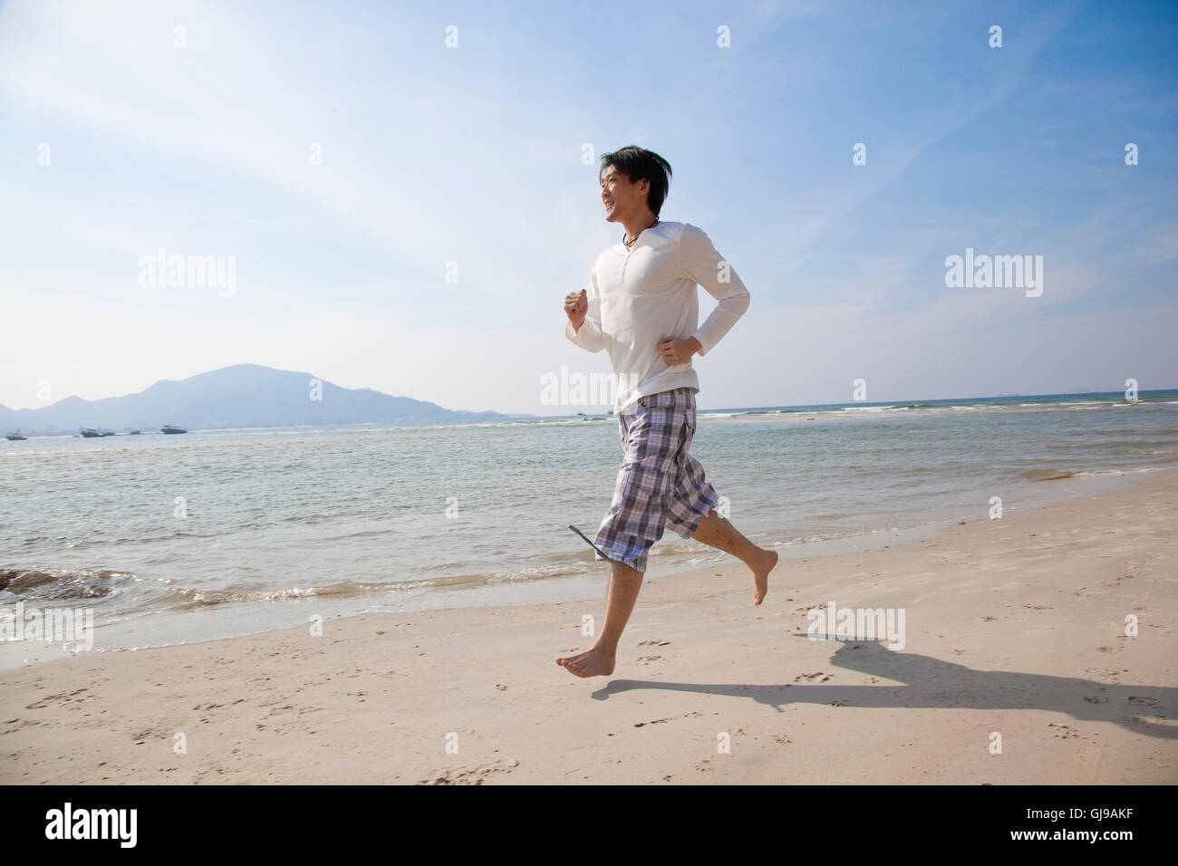 Young man running at the beach Stock Photo - Alamy