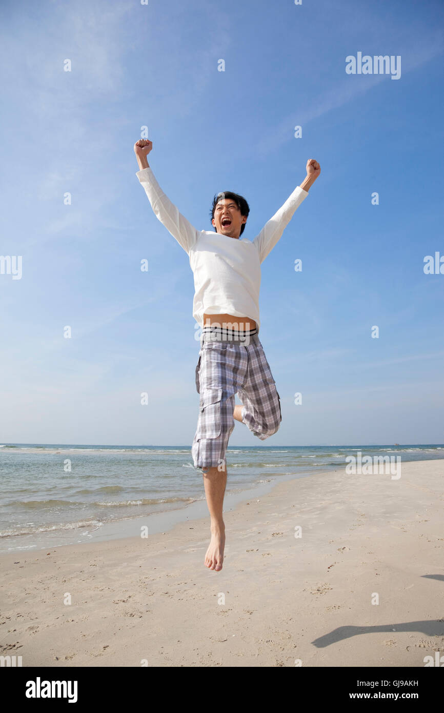 Young man jumping at the beach Stock Photo - Alamy
