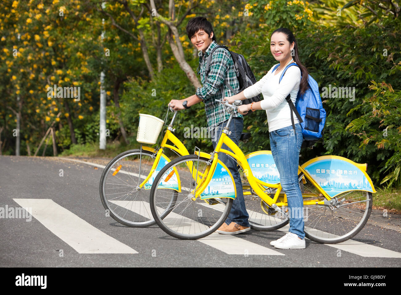 Students on campus Young couple crossing the road cycling Stock Photo ...