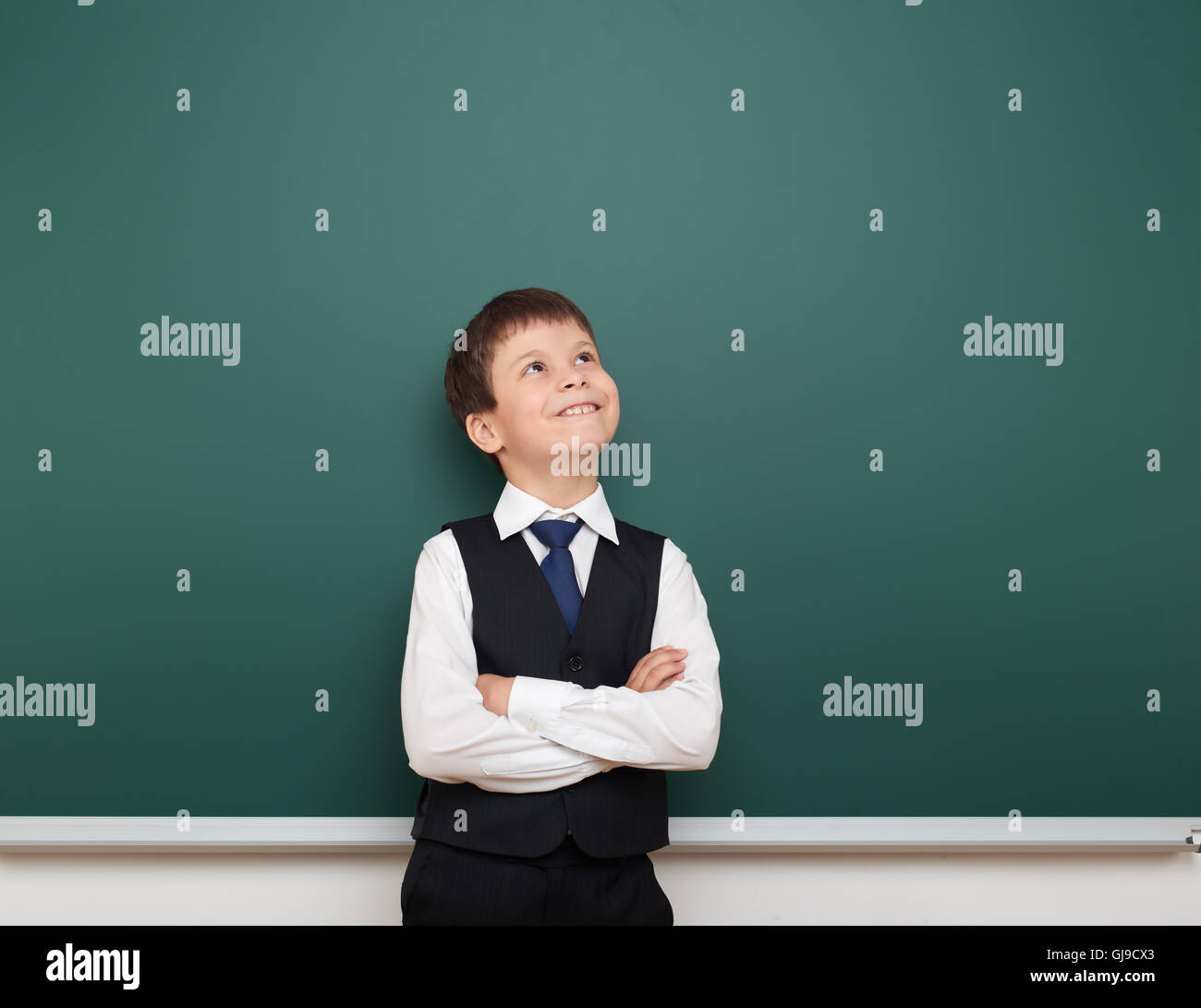 school student boy look up at the clean blackboard, grimacing and ...