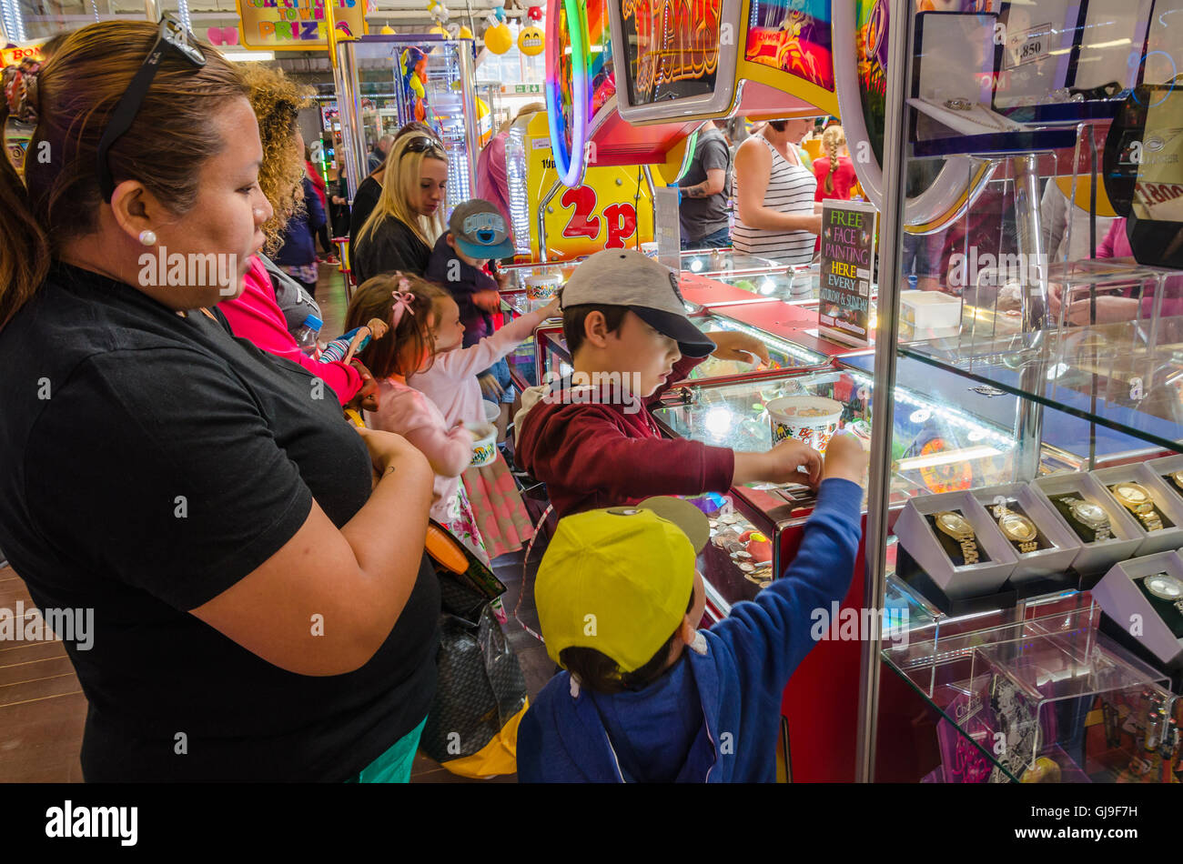 A Mum watches her two young boys playing on a 2p coin drop machine ...