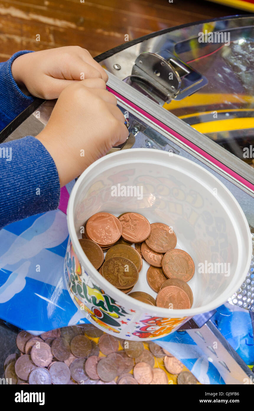 A young boy plays on a 2p slot machine in a arcade at a holiday resort ...