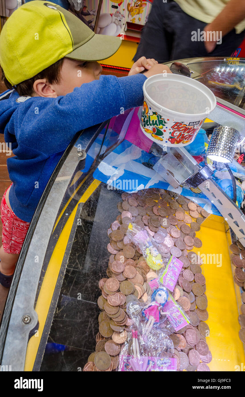 A young boy plays on a 2p slot machine in a arcade at a holiday resort ...