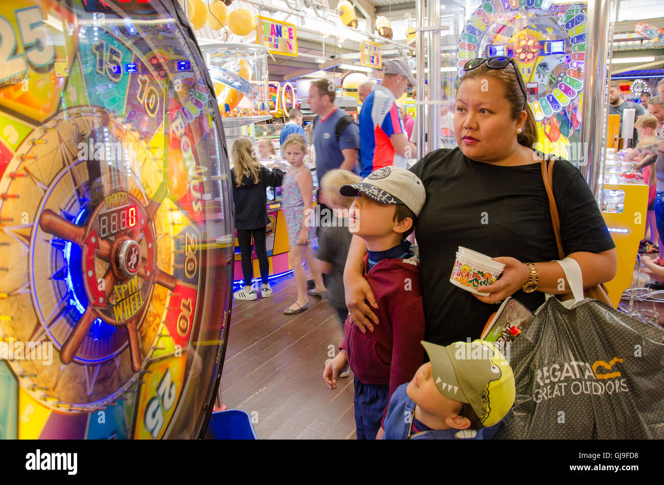 A young family play a 'spin the wheel' game in an amusement arcade ...