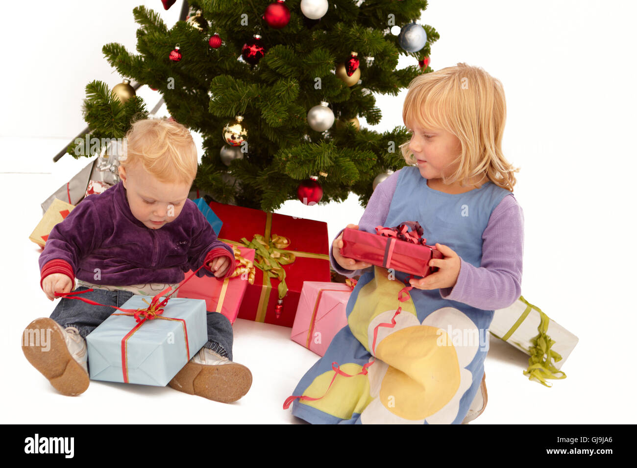 Christmas - Kids opening presents under tree Stock Photo - Alamy