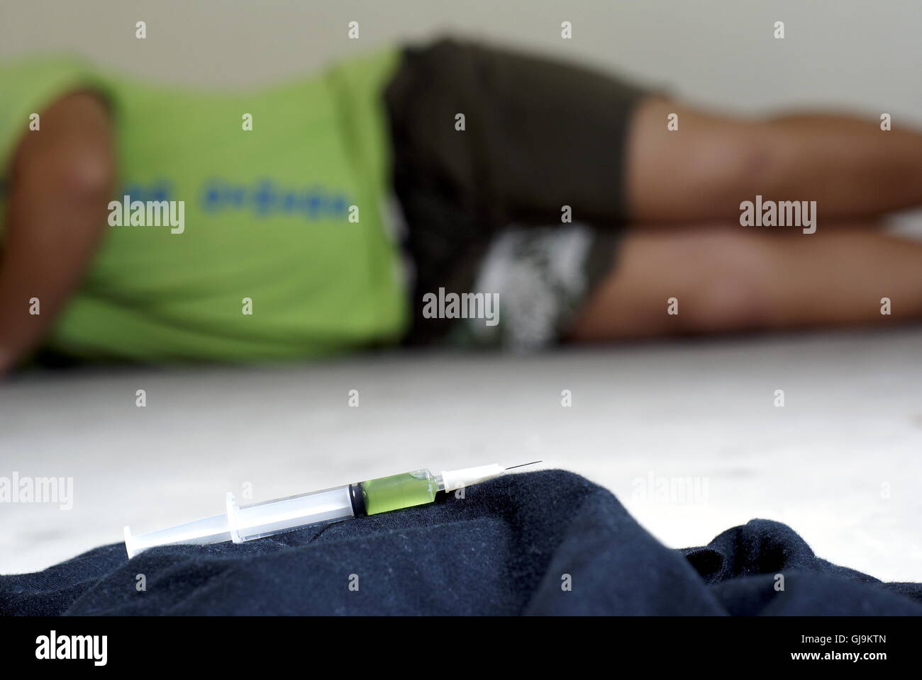 Unconscious addict and syringe on floor in foreground Stock Photo - Alamy