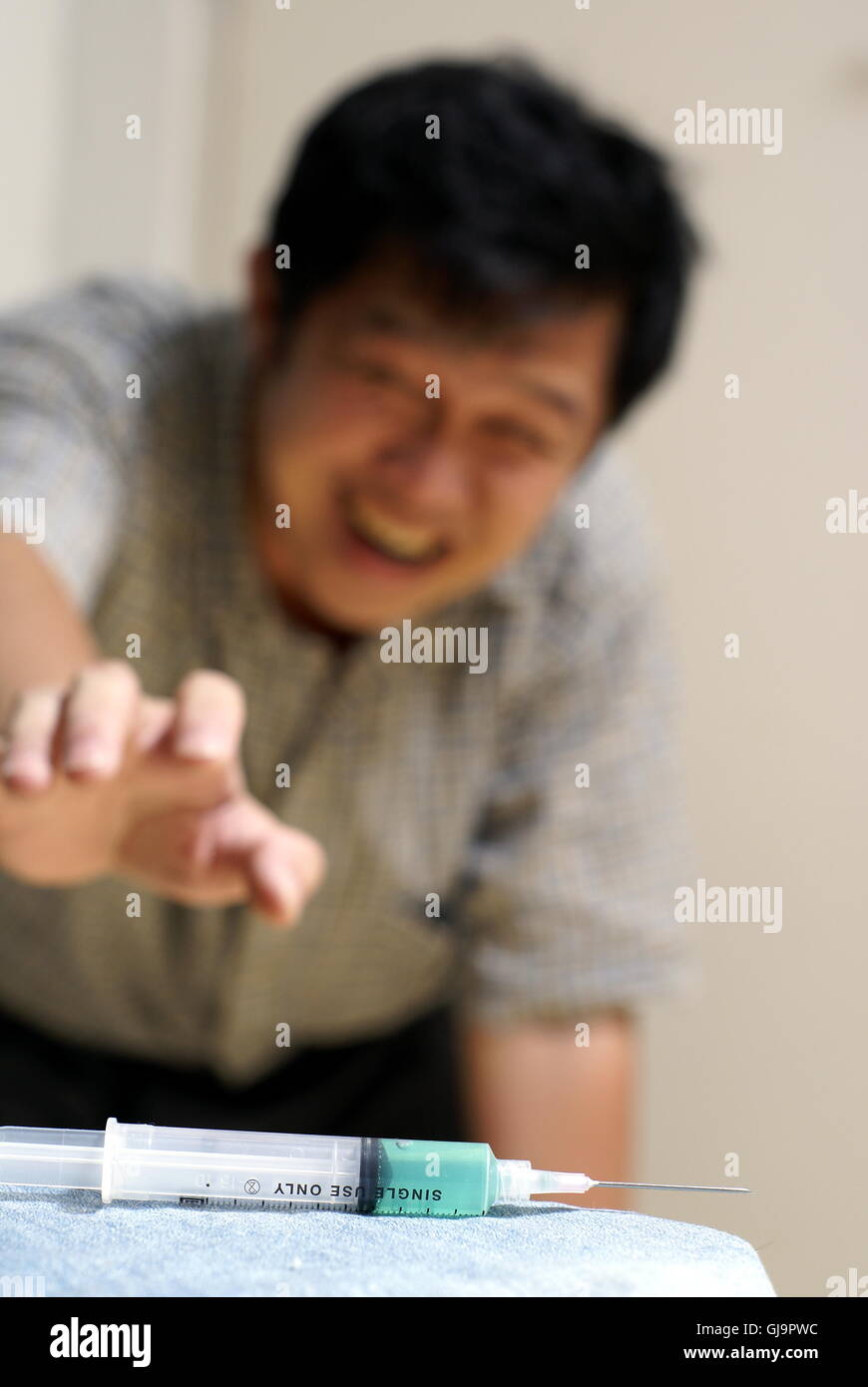 Sick male addict reaching for syringe Stock Photo - Alamy
