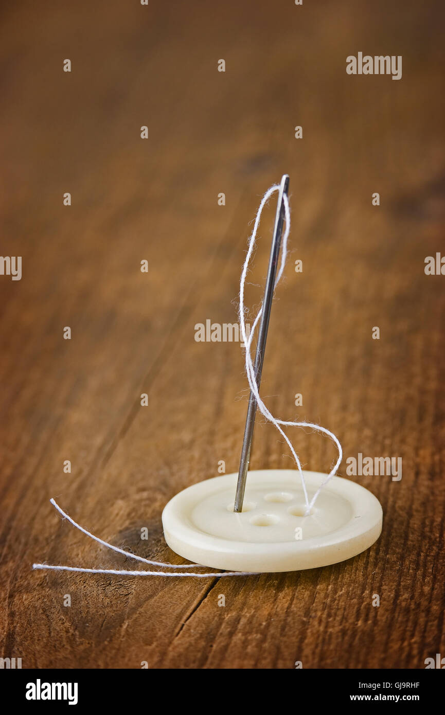 Buttons with needle and thread Stock Photo - Alamy