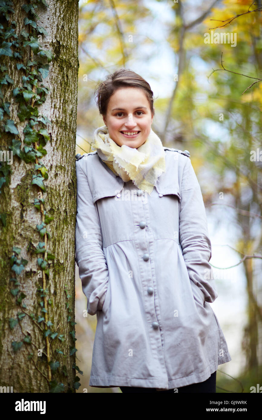 Trendy young woman standing beside a tree Stock Photo - Alamy