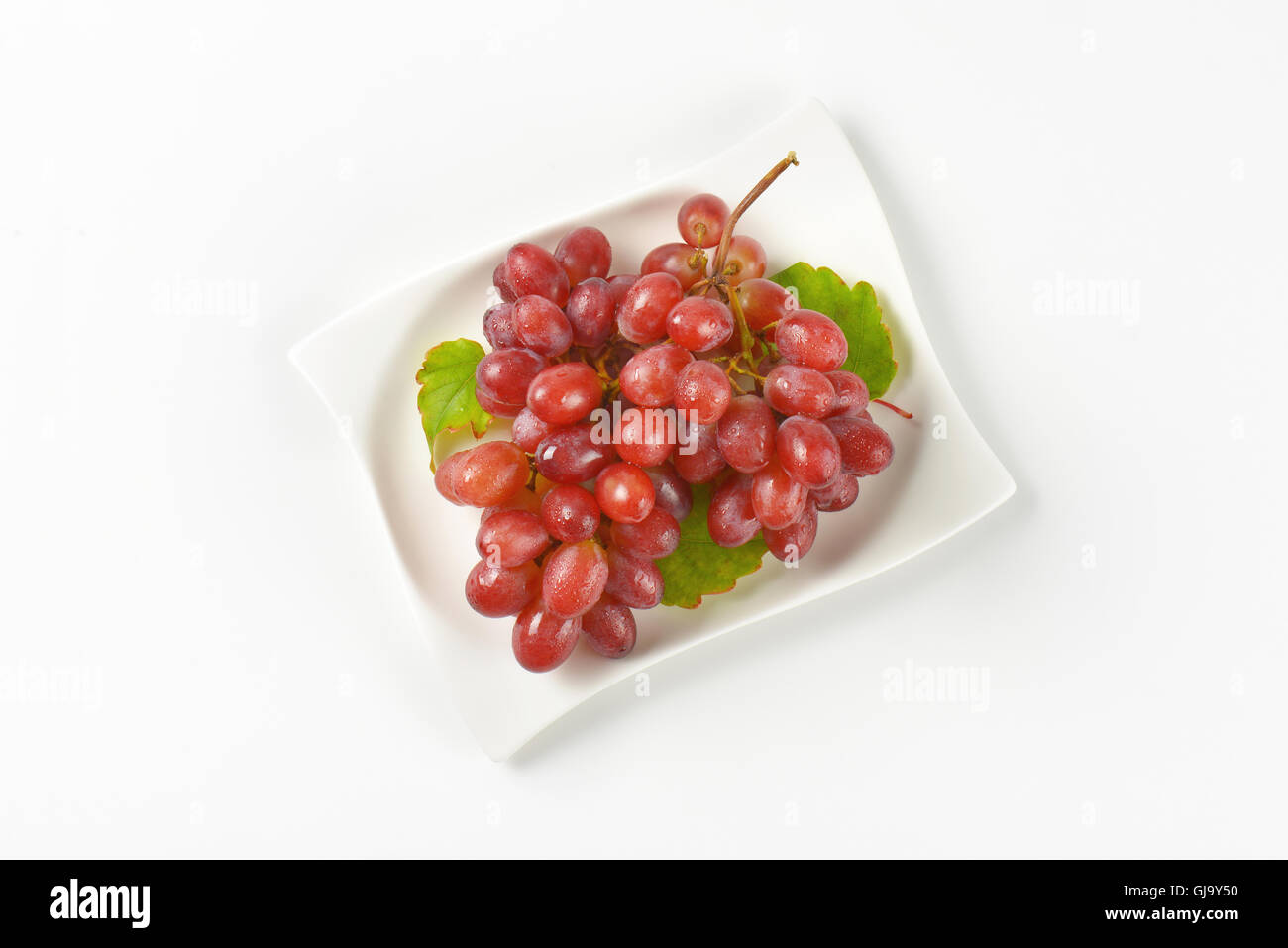 bunch of washed red grapes on white square plate Stock Photo - Alamy