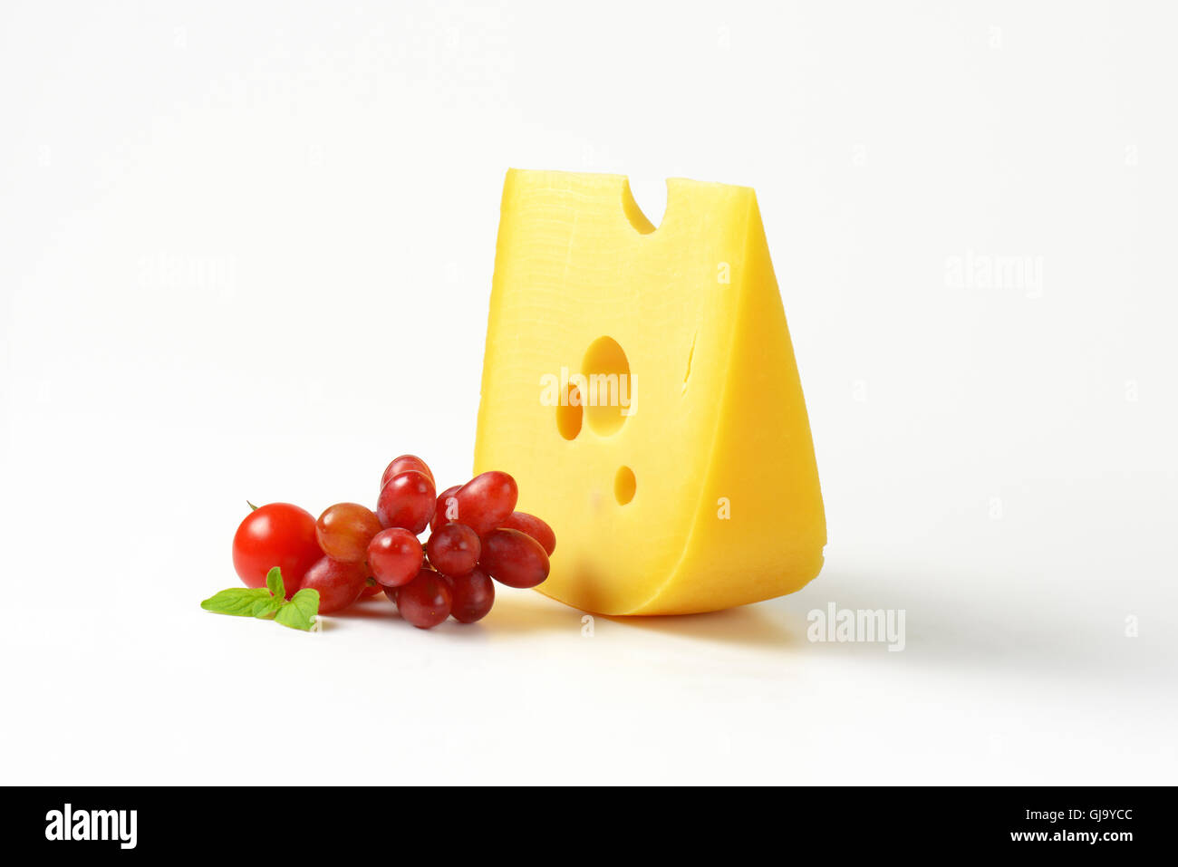 wedge of fresh cheese with red grapes on white background Stock Photo ...
