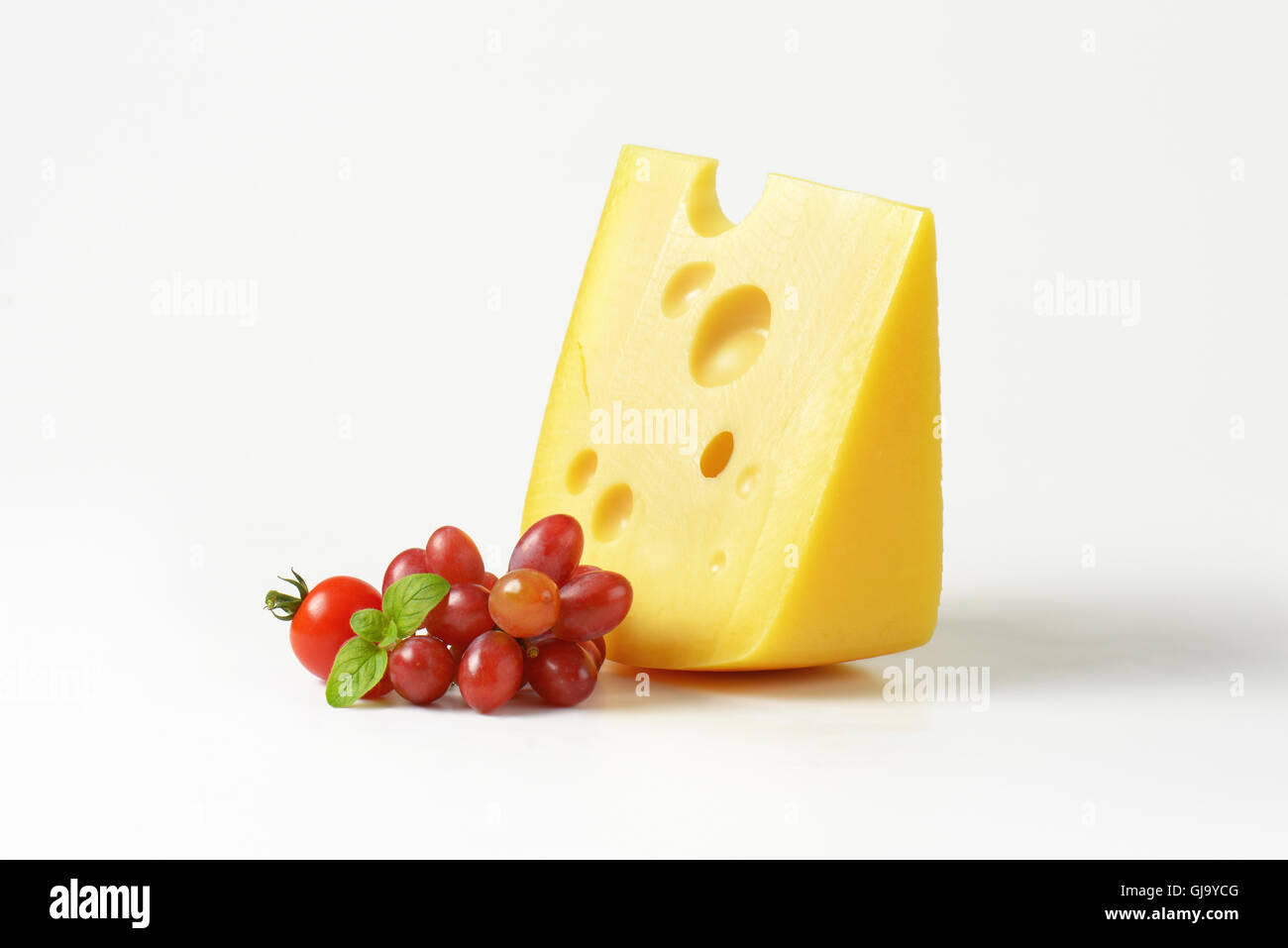 wedge of fresh cheese with red grapes on white background Stock Photo ...