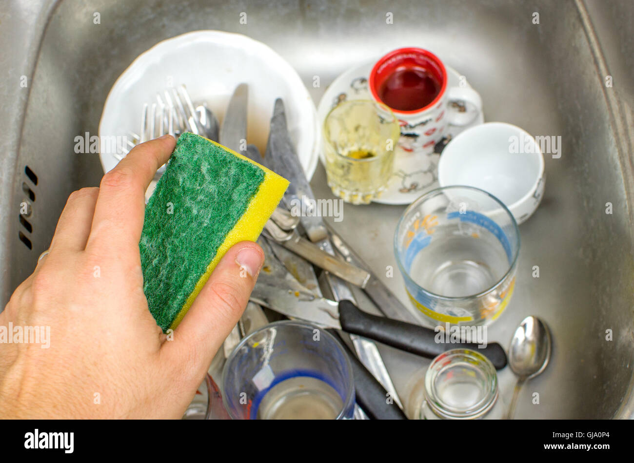 chores, washing dishes in the sink with a sponge in hand Stock Photo ...