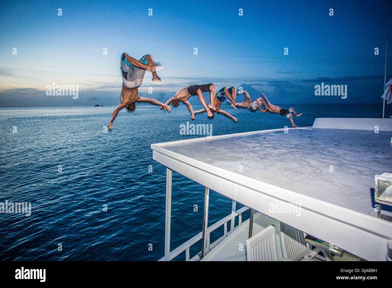 five men are jumping synchronically with backflip from boat Stock Photo ...