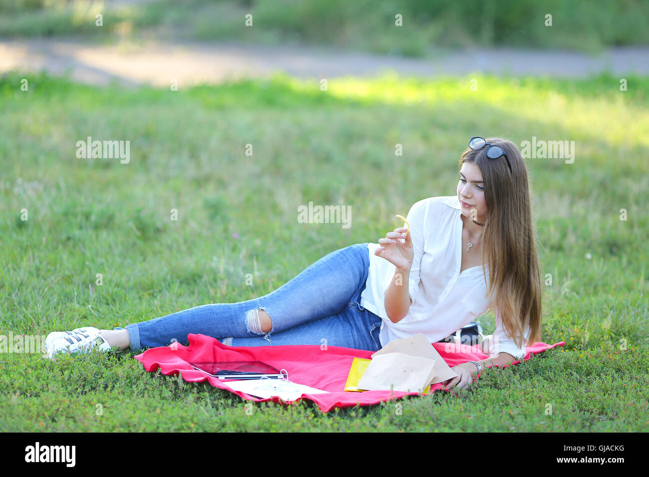 girl lying on the nature and eateth fast food. student working in the ...