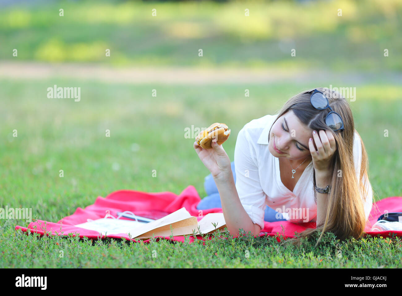 girl lying on the nature and eateth fast food. student working in the ...