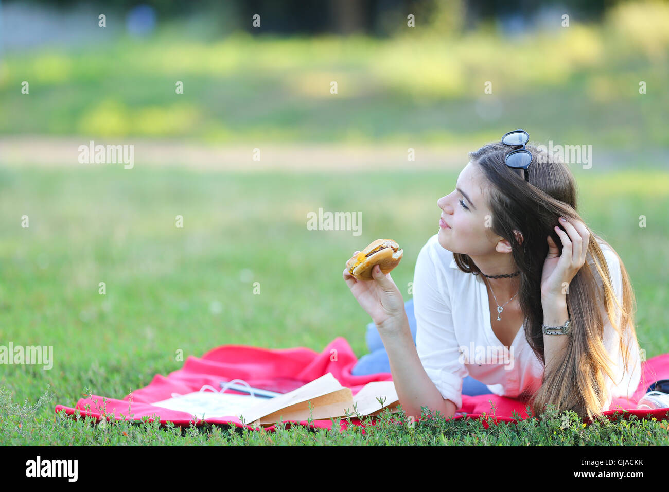 girl lying on the nature and eateth fast food. student working in the ...