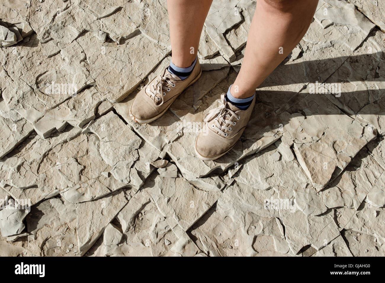 Female and male feet in casual shoes are standing on natural stone ...