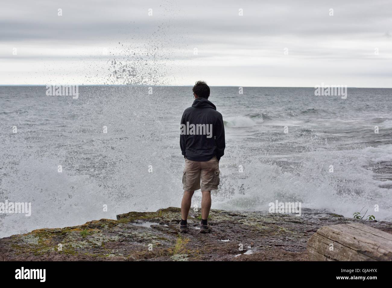 A young man seen from behind, looking out over turbulent water at Lake ...