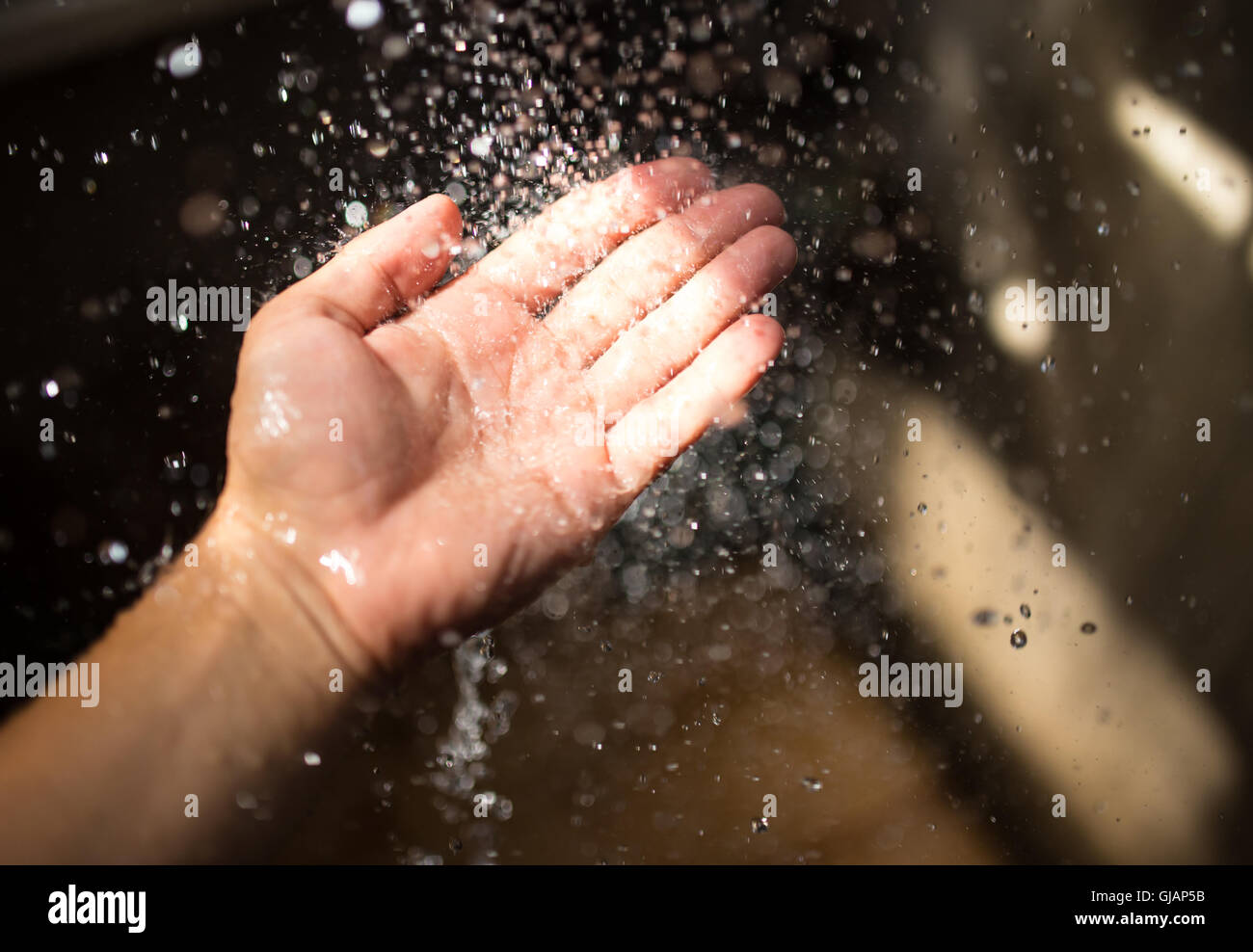Human hand in sunlight under falling water Stock Photo - Alamy