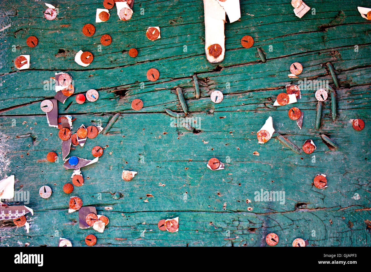Rotten pins on green scratched wooden board with torn peaces of old ...