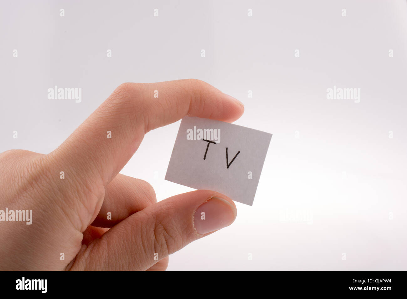 Hand holding a TV written little white paper in with fingers on white ...