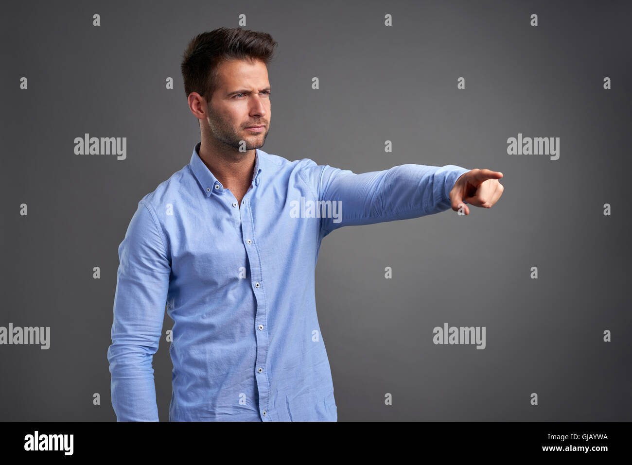 A serious handsome young man pointing in a studio Stock Photo - Alamy