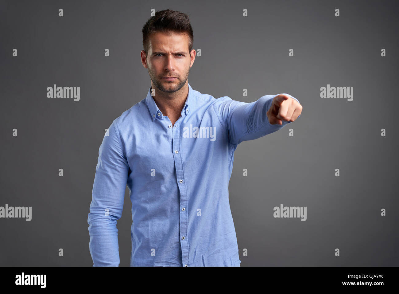 A serious handsome young man pointing in a studio Stock Photo - Alamy