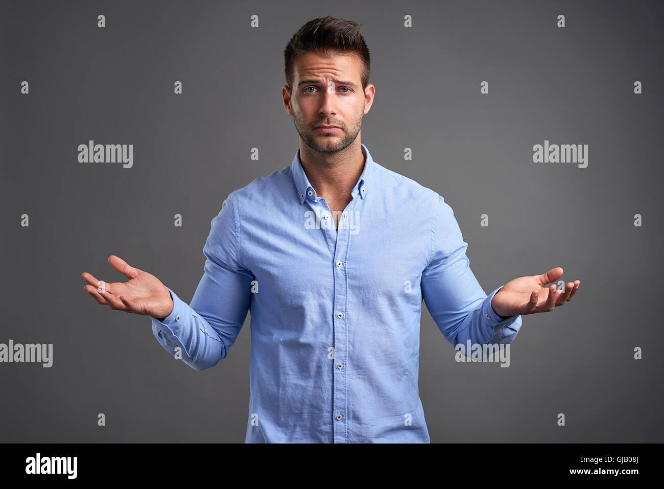 A handsome young man looking uncomprehendingly in to the camera in ...