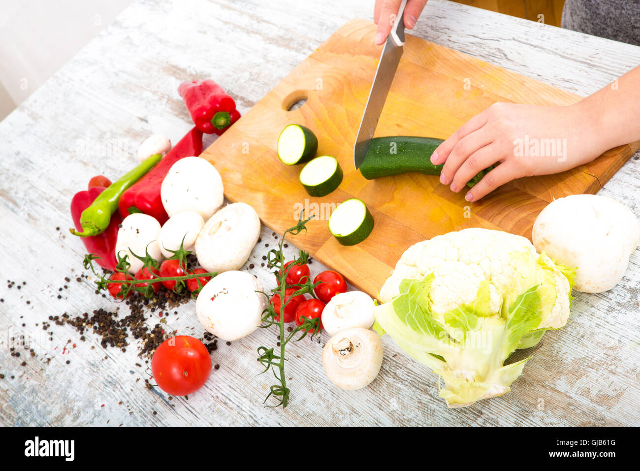 A woman chopping up vegetables at a table Stock Photo - Alamy