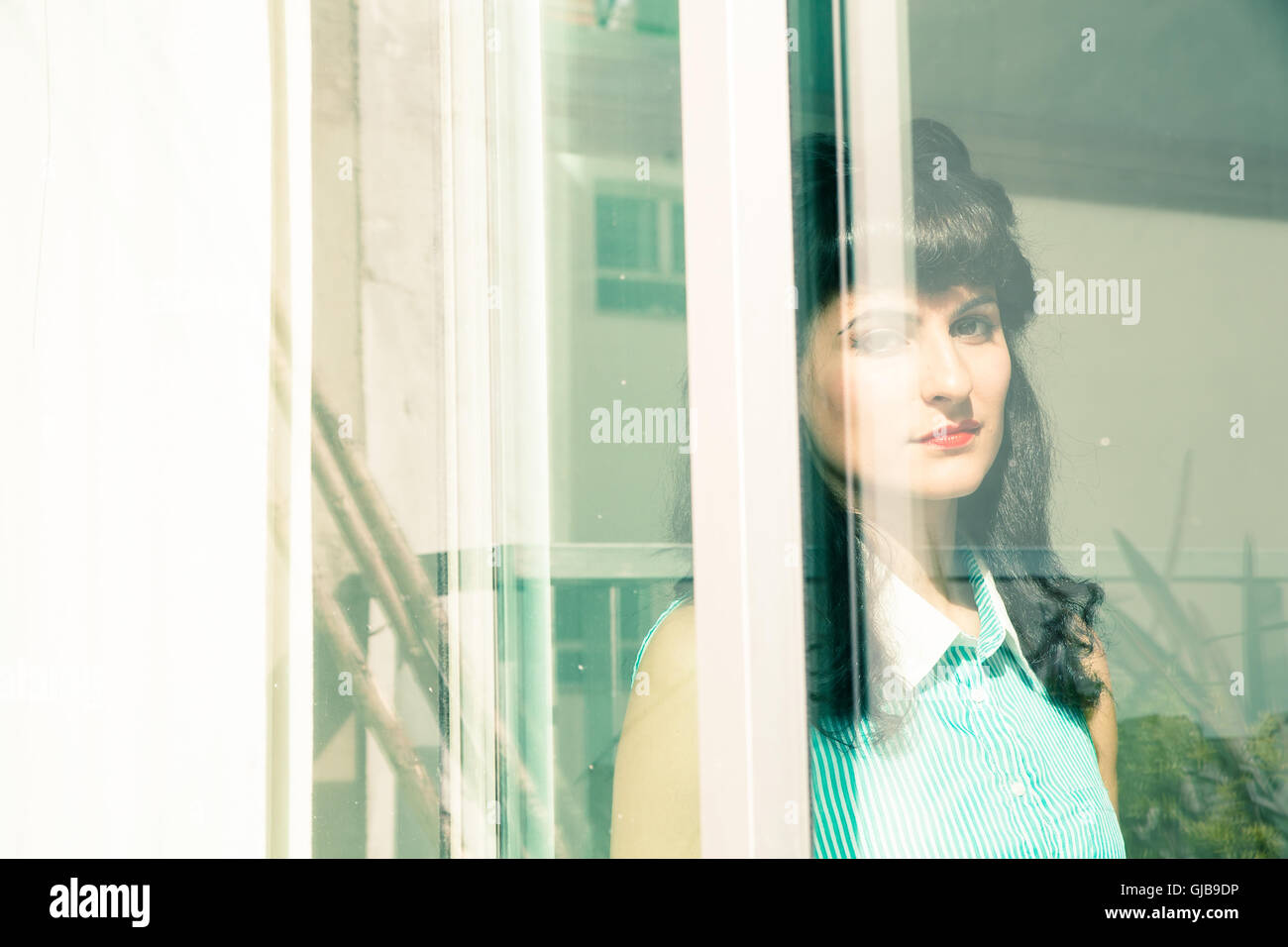 A vintage styled woman sitting beside the window Stock Photo - Alamy
