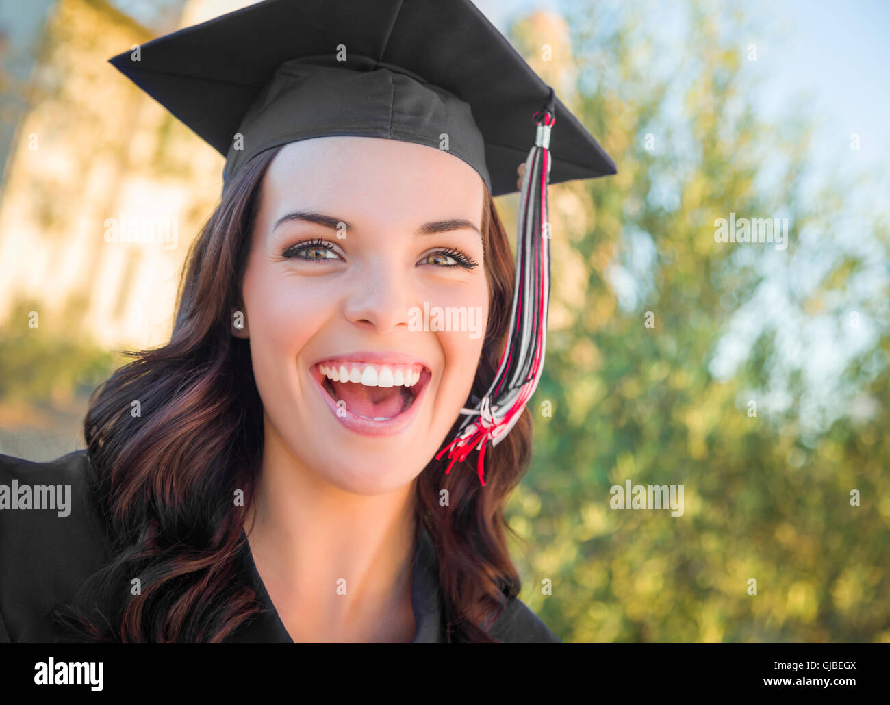 Happy Graduating Mixed Race Woman In Black Cap and Gown Celebrating on ...