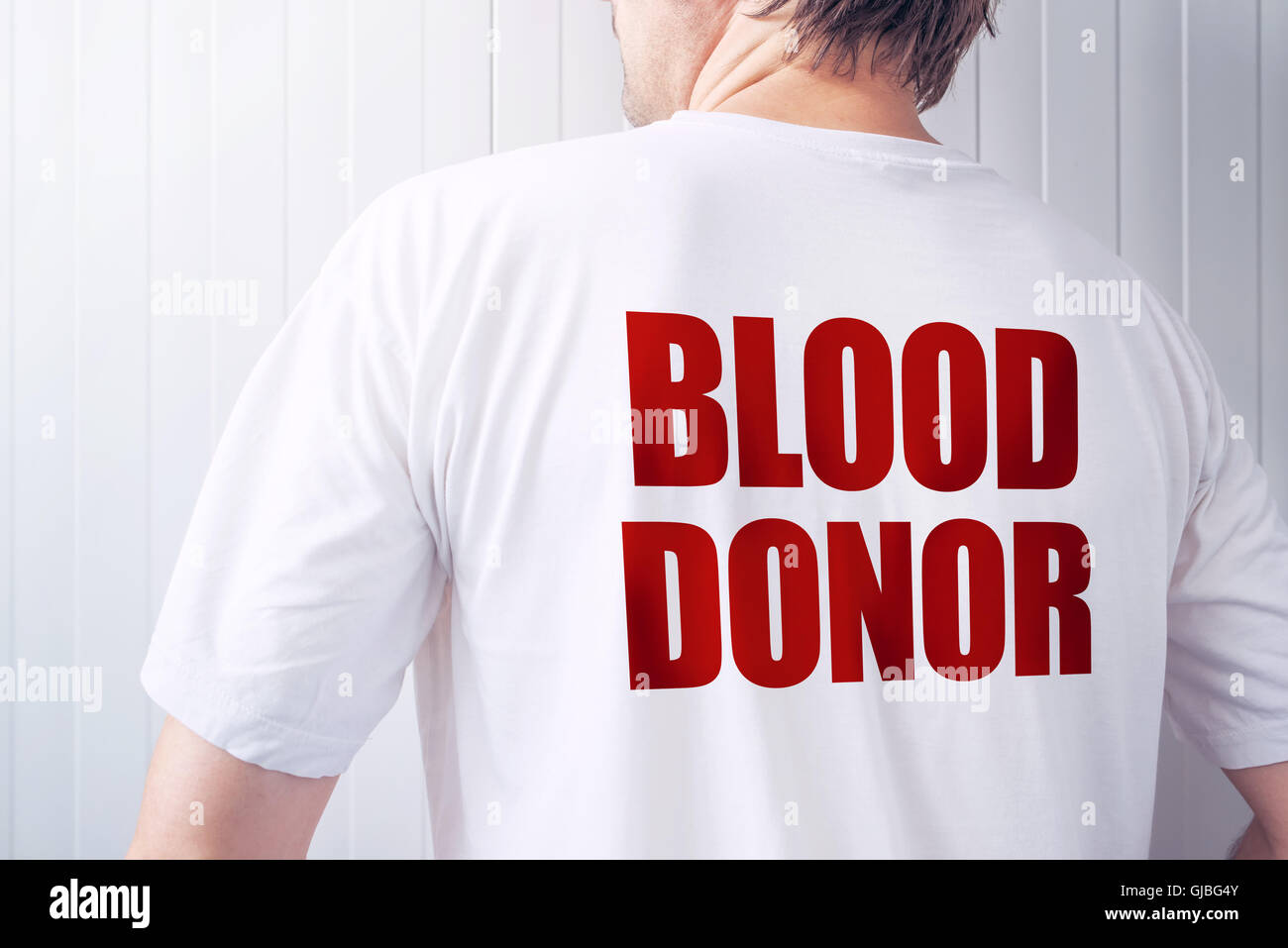 Male blood donor wearing white t-shirt, person from behind posing at ...