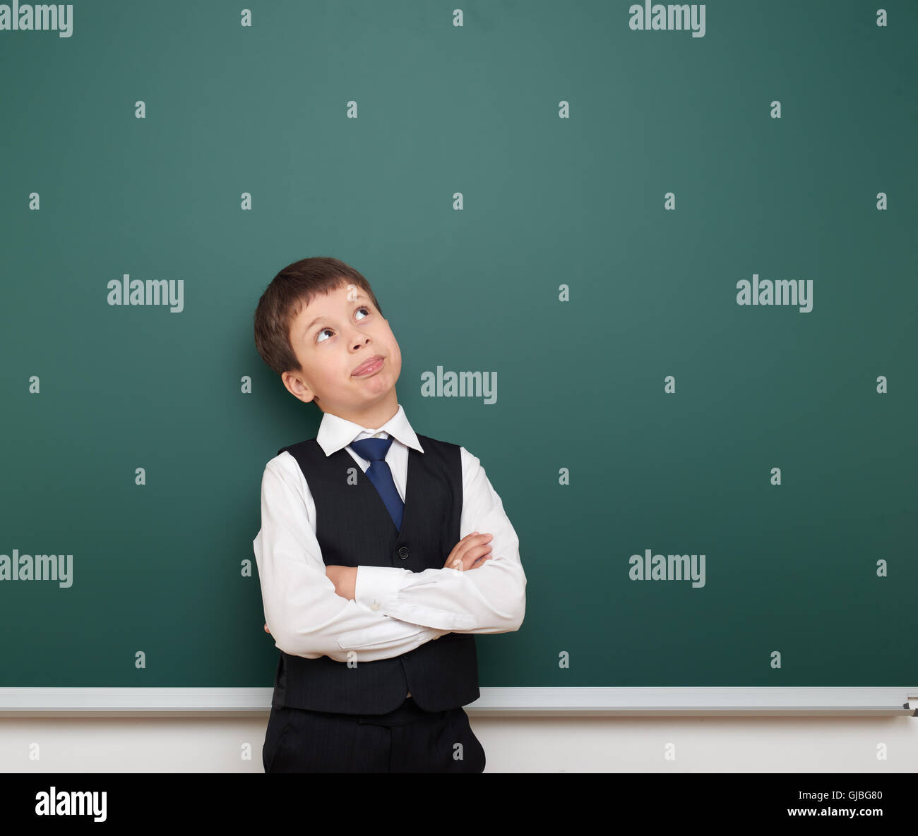 school student boy look up at the clean blackboard, grimacing and ...