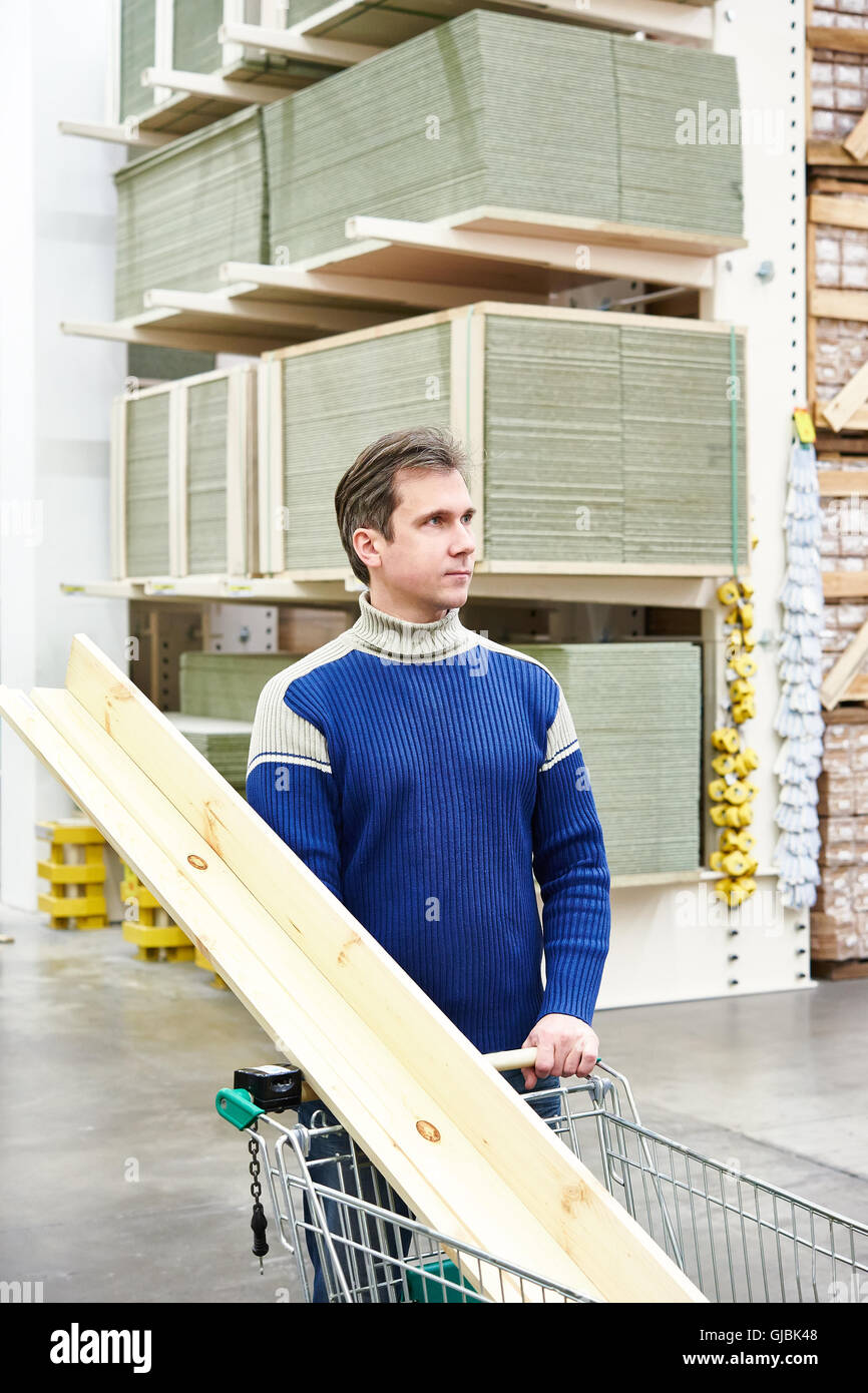 Man chooses boards for the construction of the store Stock Photo - Alamy