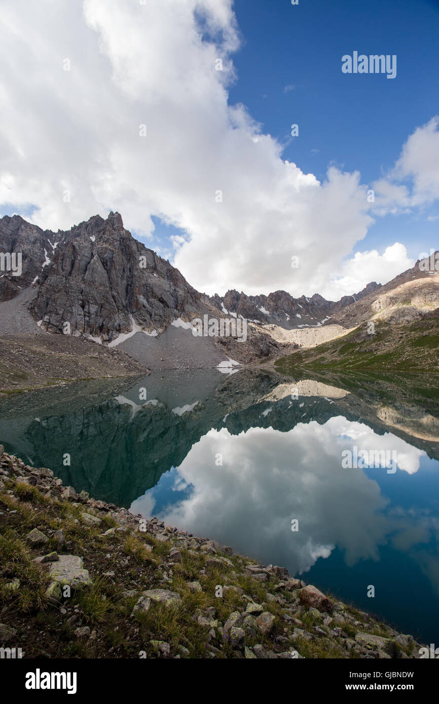 Reflections of rocks and sky in a small Ala-Too mountain lake in the ...