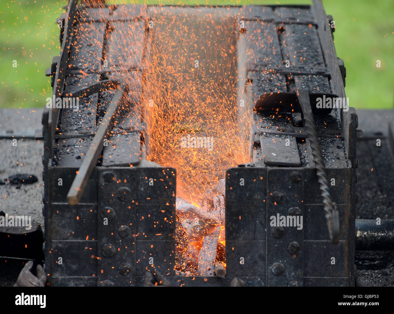 Sparks fly from a smith's forge where coal burns while the bellows blow ...