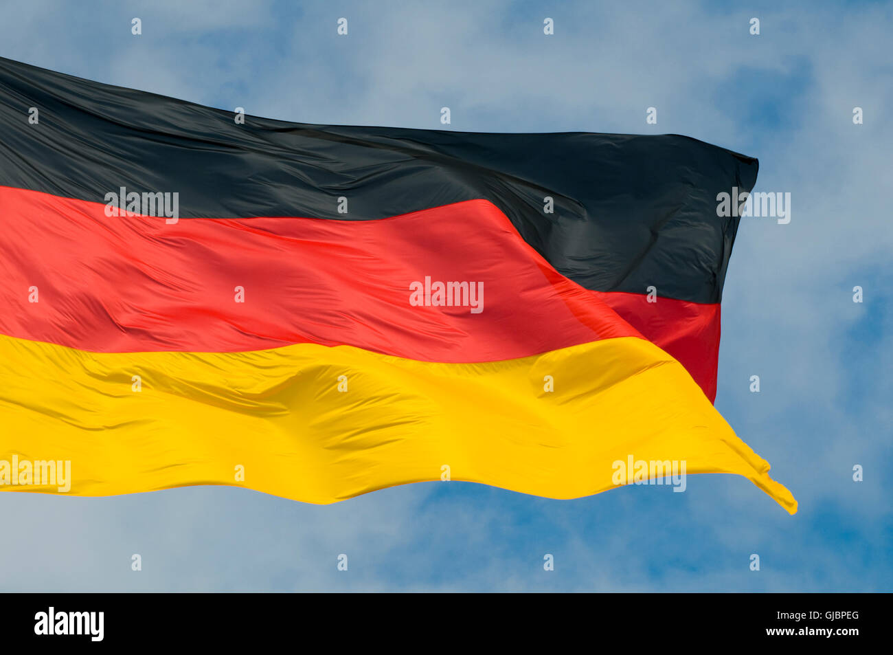 The German flag flying against a partly cloudy sky Stock Photo - Alamy