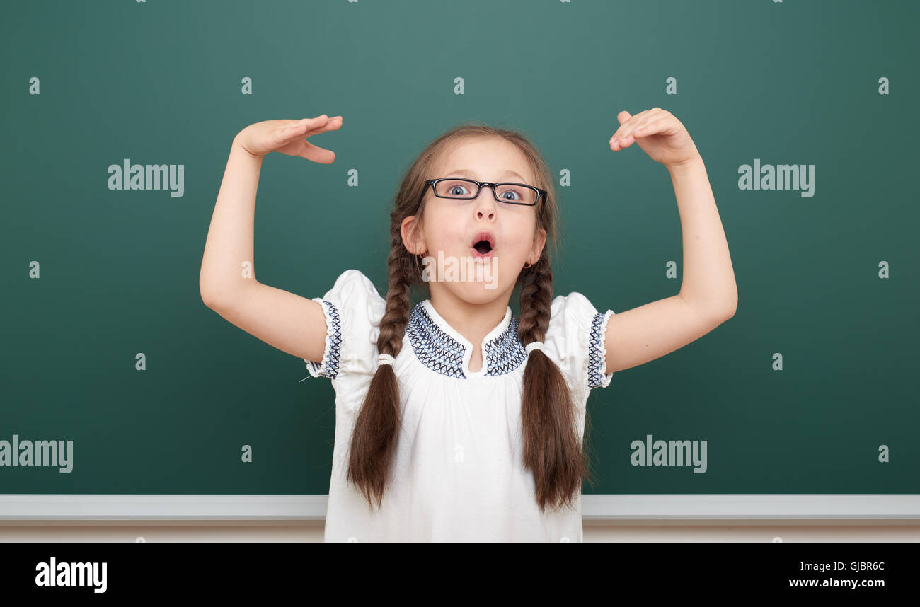 school student girl open arms at the clean blackboard, grimacing and ...