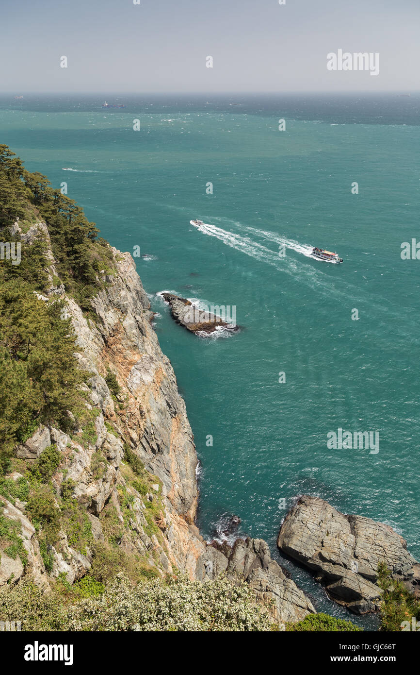 View of a steep and rocky cliff, ocean and a motorboat from above at ...