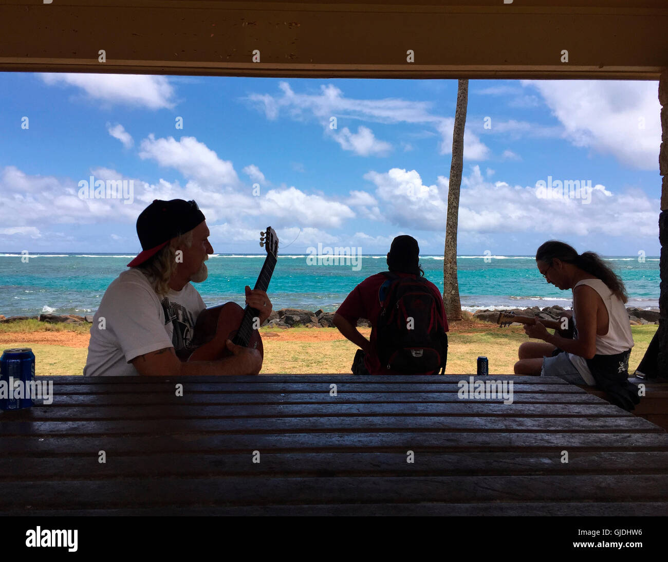 Three local musicians silhouetted against the blue ocean and sky ...