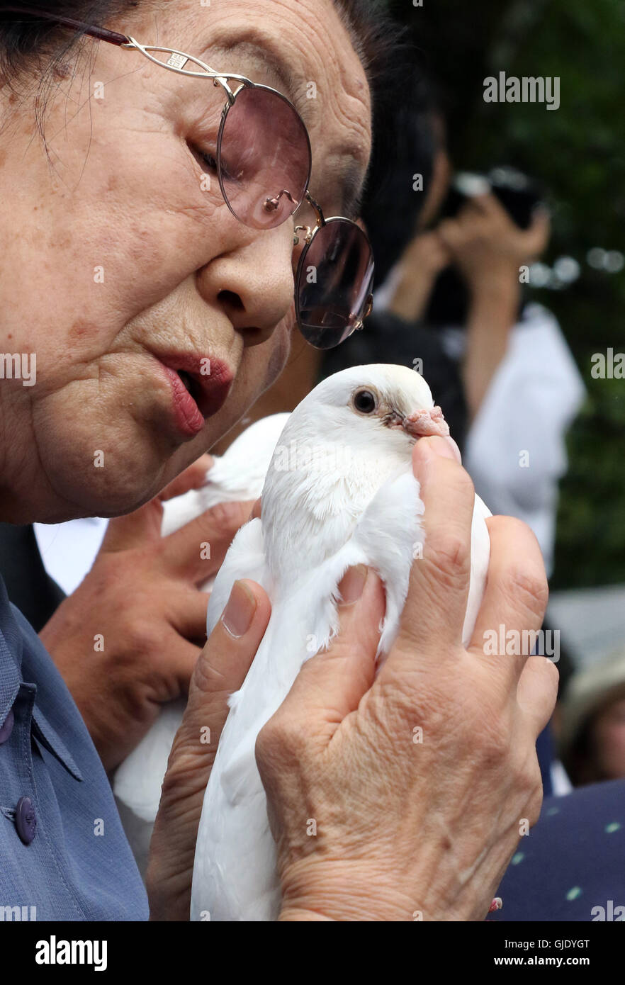 Tokyo, Japan. 15th Aug, 2016. A woman holds a dove as people release ...