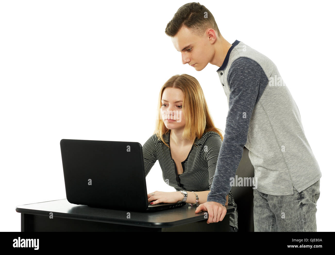 Two teenagers classmates working together, the boy is helping the girl ...