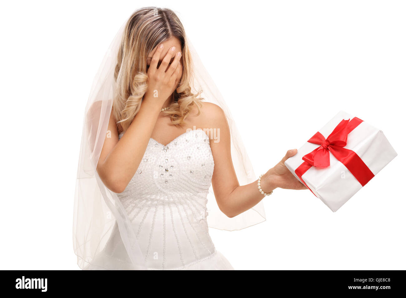 Young disappointed bride holding a wedding present in her hand isolated ...