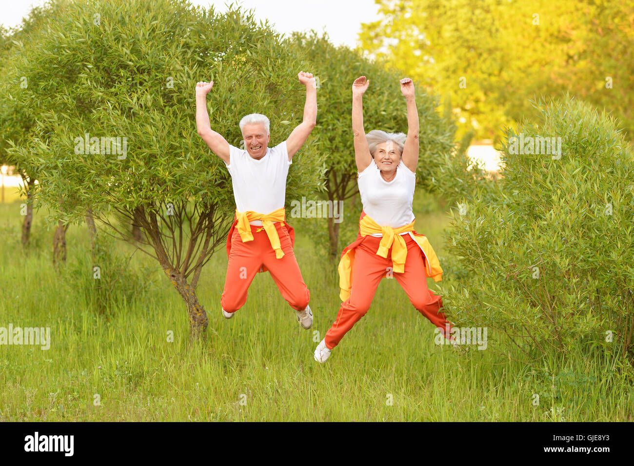 Happy fit senior couple jumping Stock Photo - Alamy