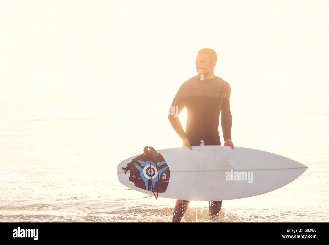 A surfer with his surfboard at the beach Stock Photo - Alamy