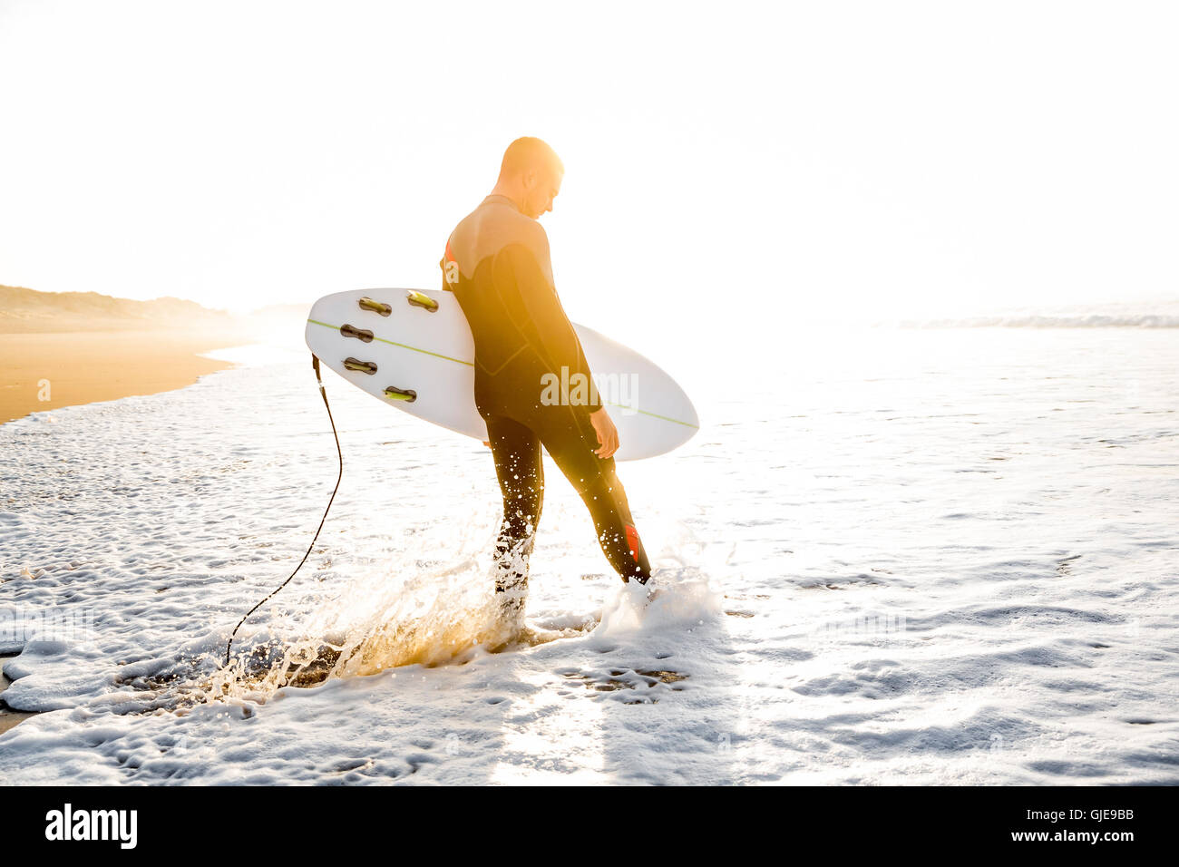 A surfer with his surfboard running to the waves Stock Photo - Alamy