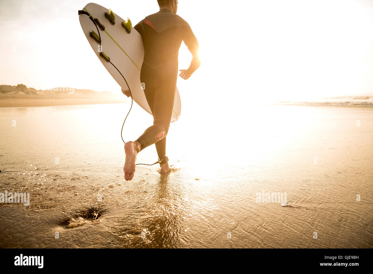 A surfer with his surfboard running to the waves Stock Photo - Alamy